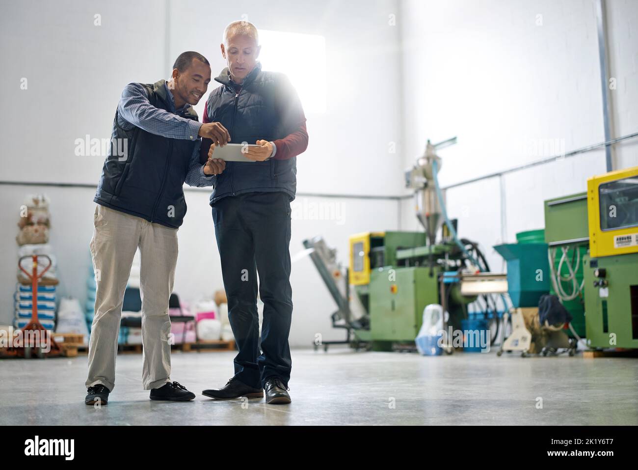 Giving his manager a status update. two factory managers using a tablet ...