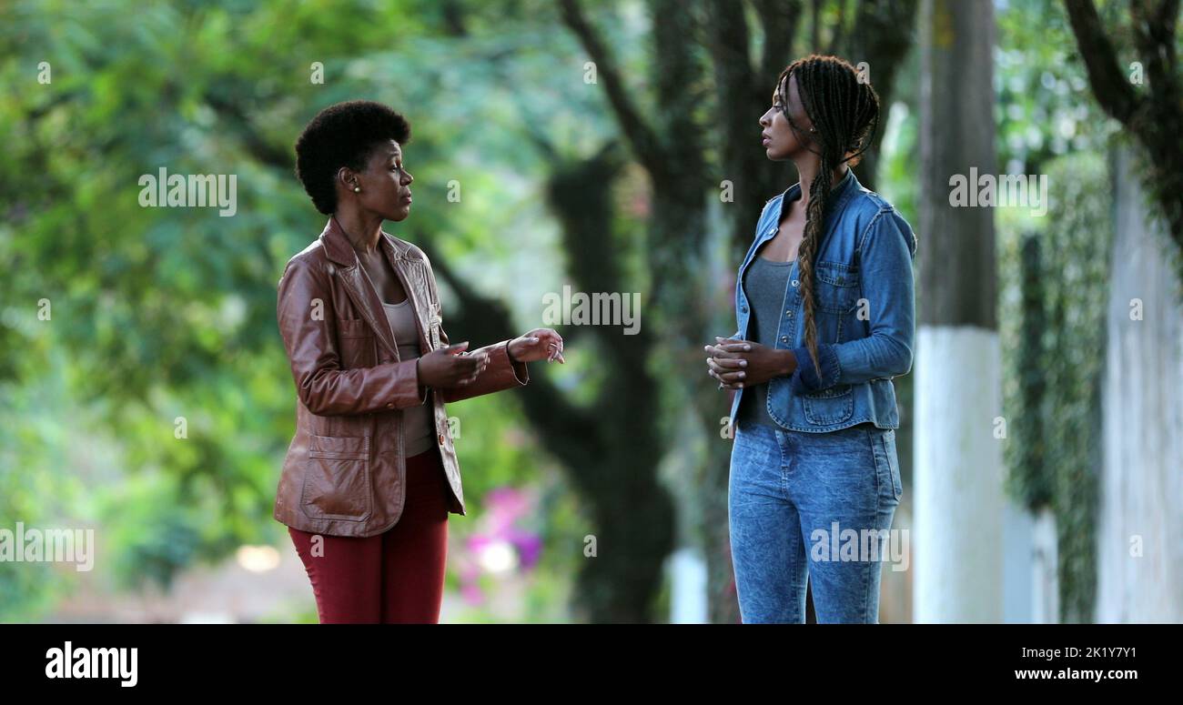 Candid African women talking outside exchanging ideas and conversation ...