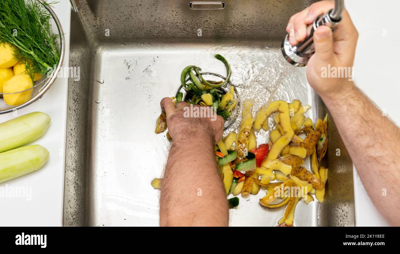 Hand removes food waste into the dispenser hole in the kitchen sink ...