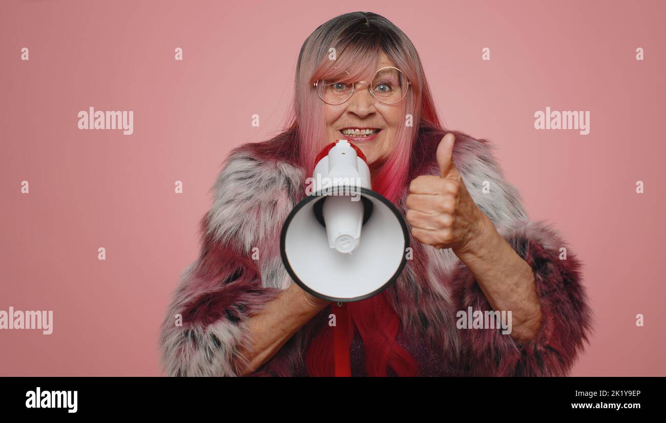 Smiling happy stylish old woman talking with megaphone, proclaiming ...