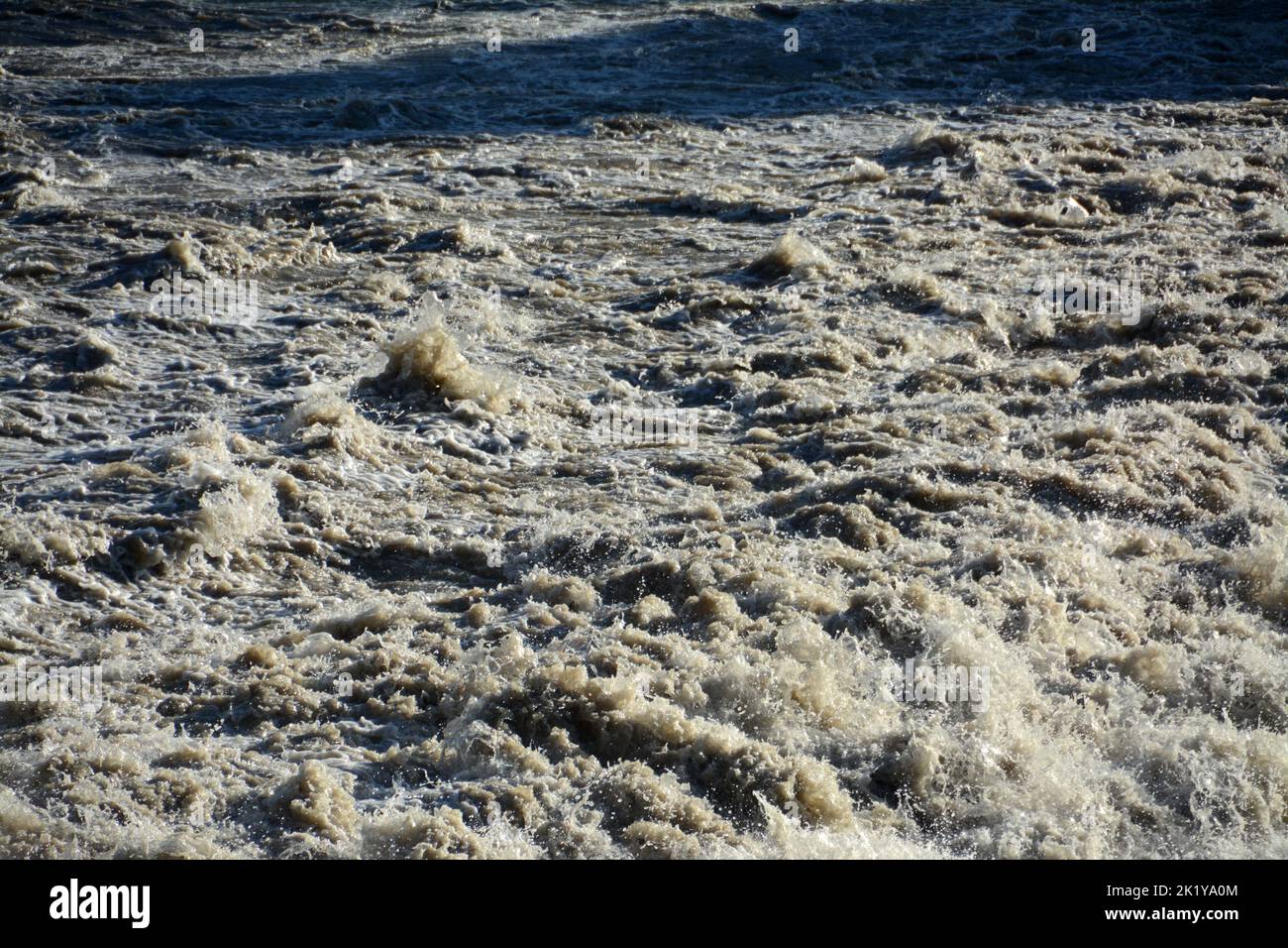 Swirling, churning waters of an earth-rich river that brings floods ...