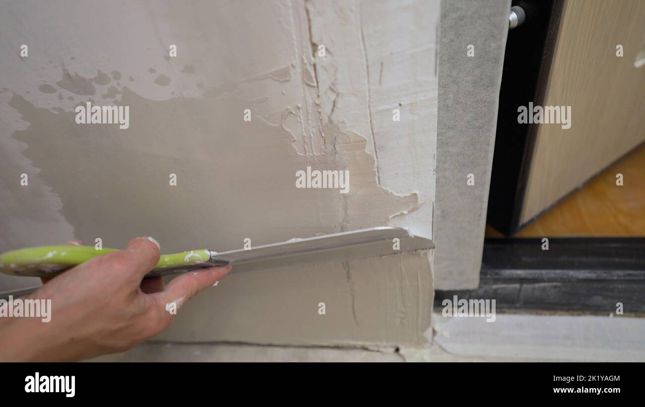 A worker man with the help of builders applies a layer of putty for the ...