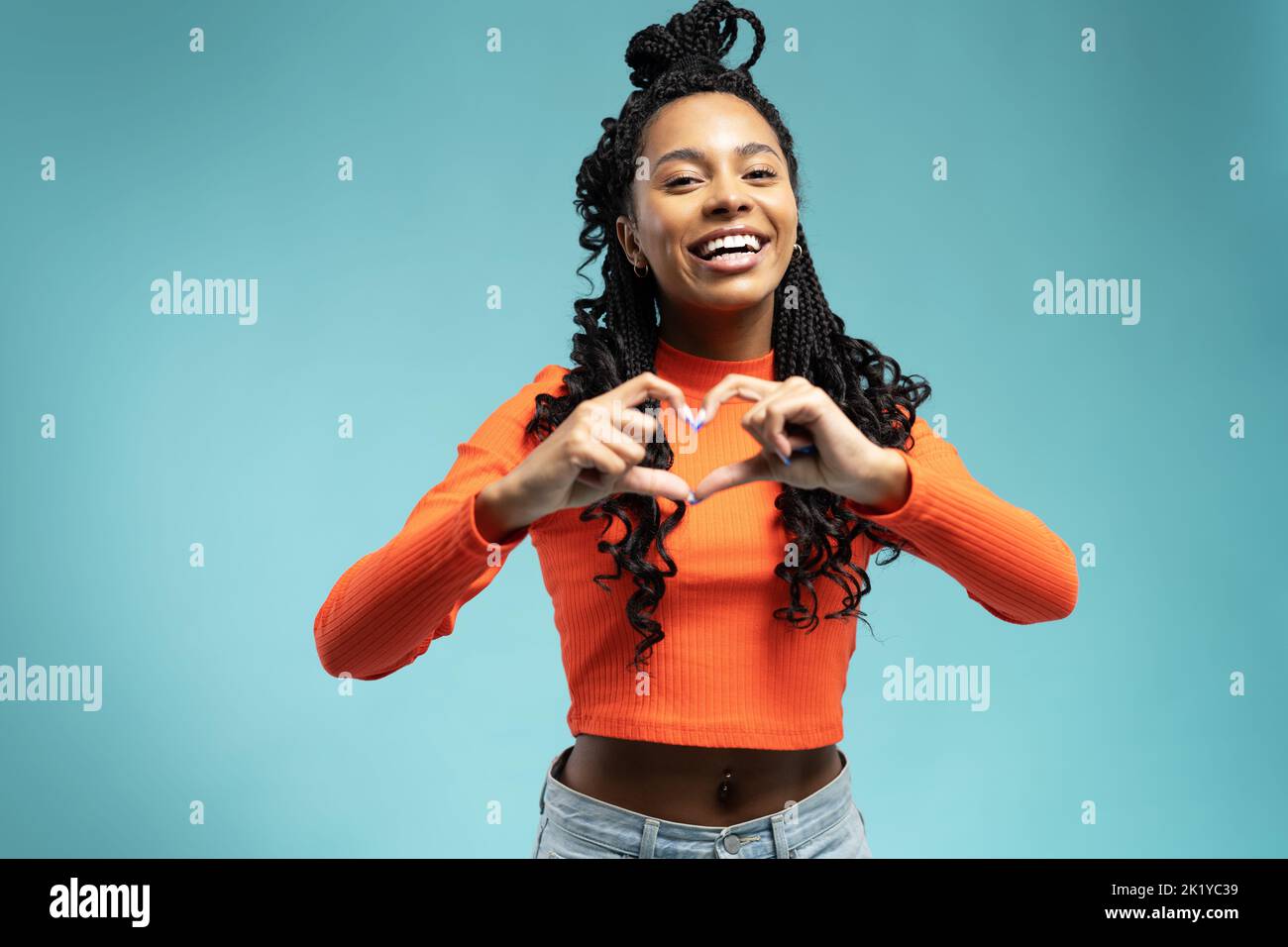 Young lovable woman with african hairstyle showing heart and laughing ...