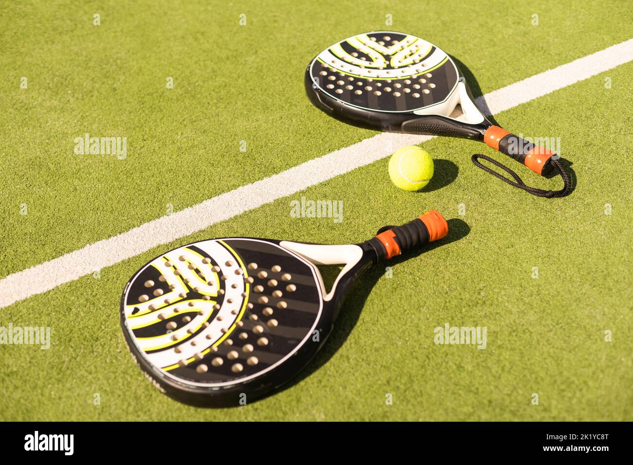 Yellow balls on grass turf near padel tennis racket behind net in green ...