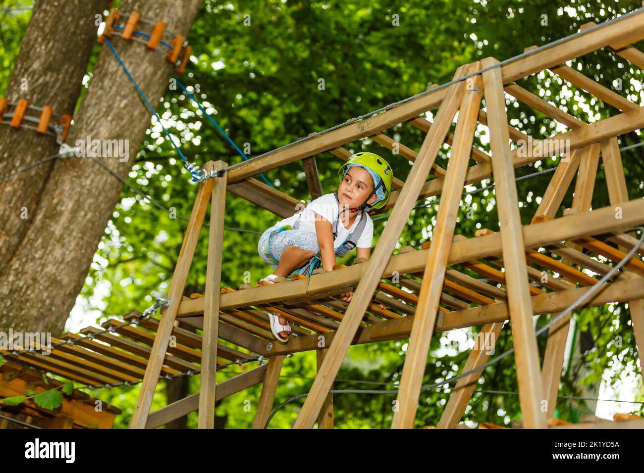 Happy school girl enjoying activity in a climbing adventure park on a ...