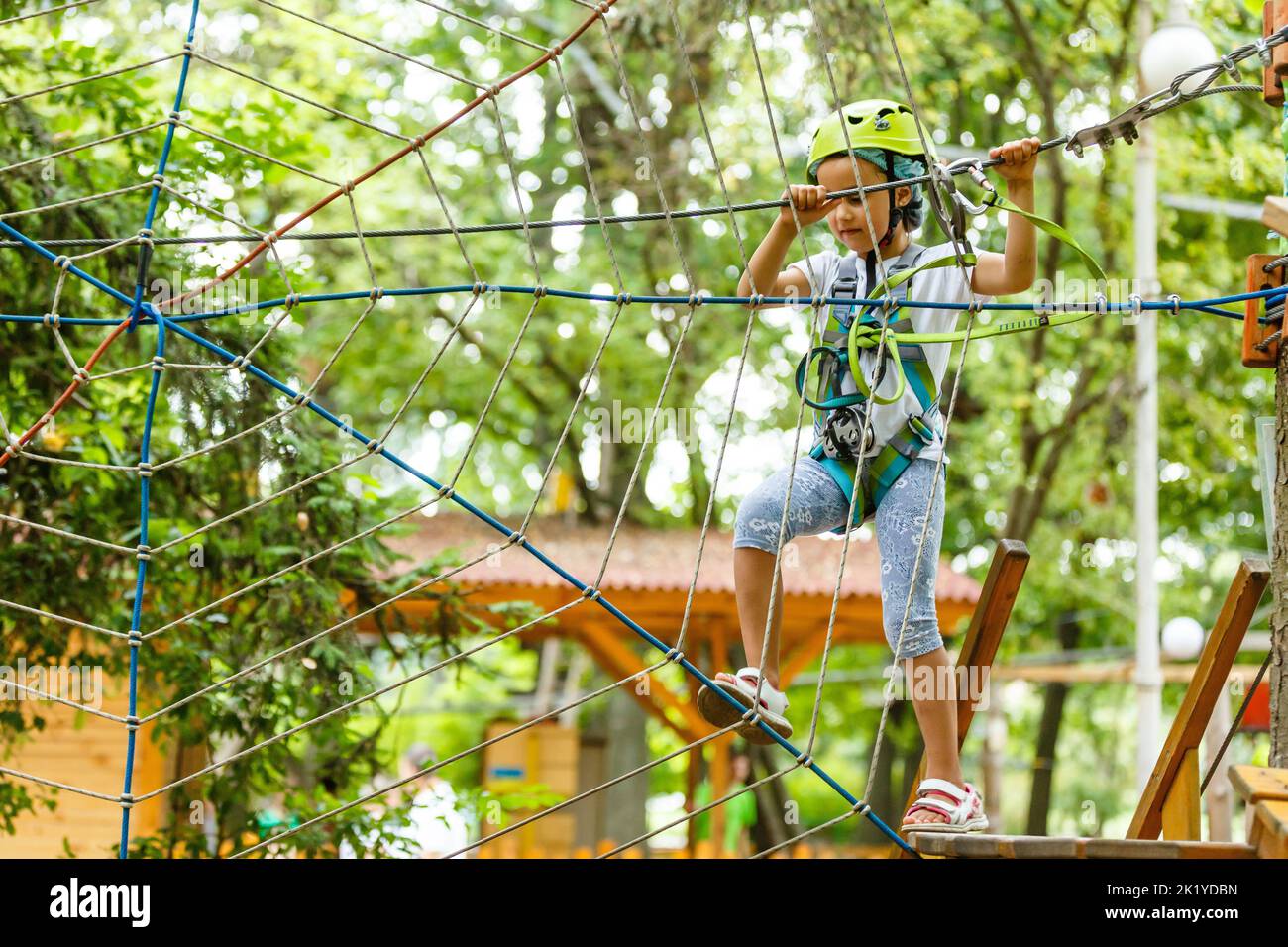 Happy school girl enjoying activity in a climbing adventure park on a ...