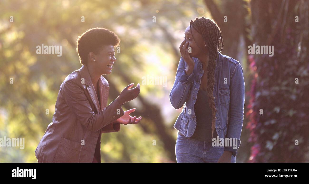 Two women laughing and smiling outside walking in street. friend ...