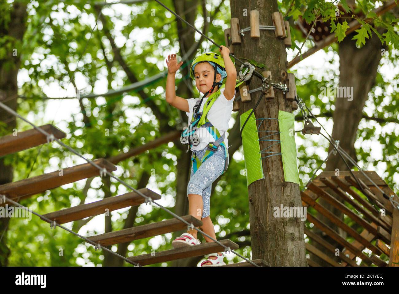 Happy school girl enjoying activity in a climbing adventure park on a ...