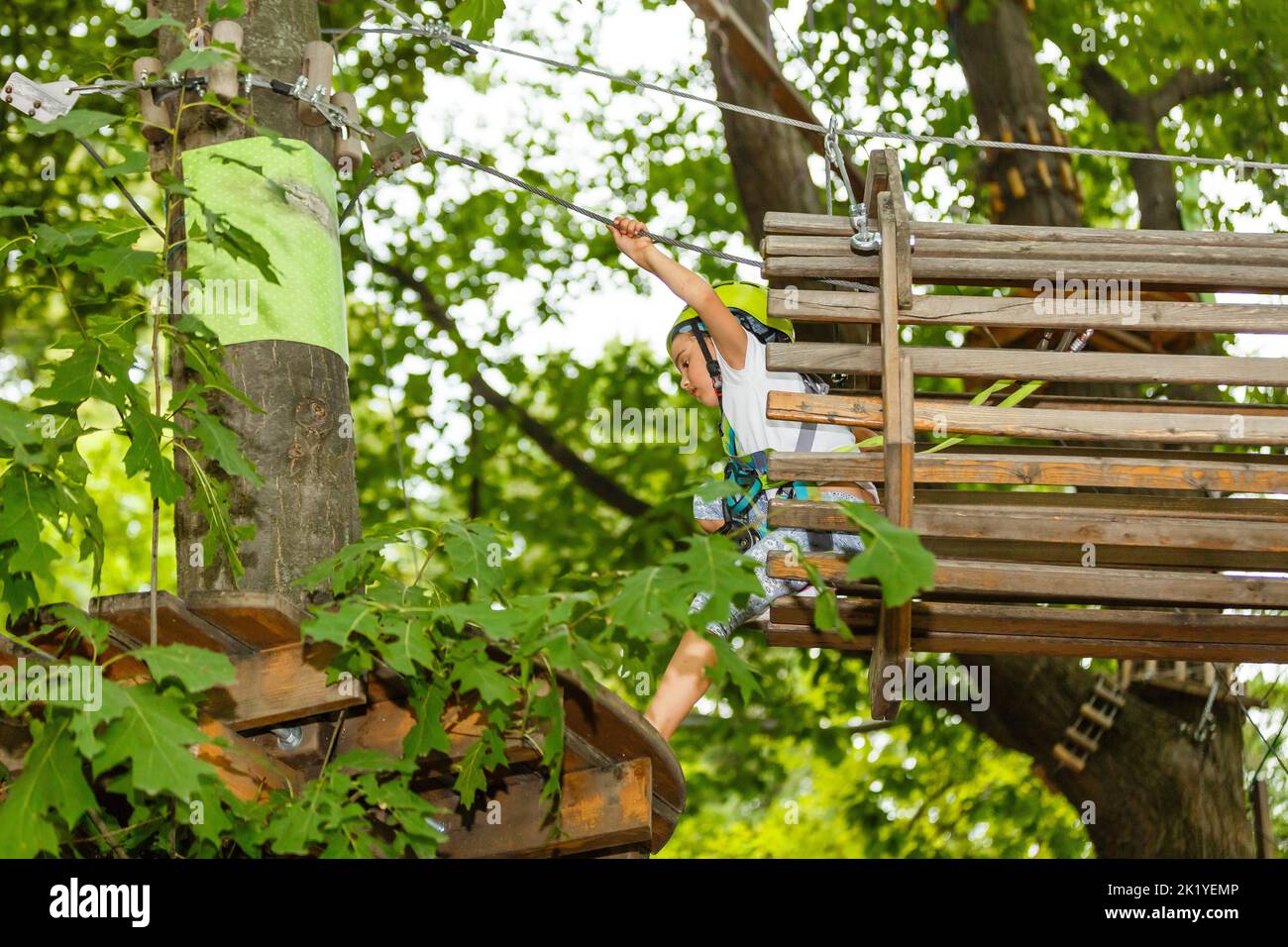 Little girl is standing on a rope, holding a rope with his hands. A ...