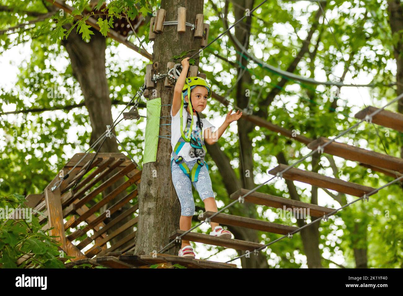 Little girl is standing on a rope, holding a rope with his hands. A ...