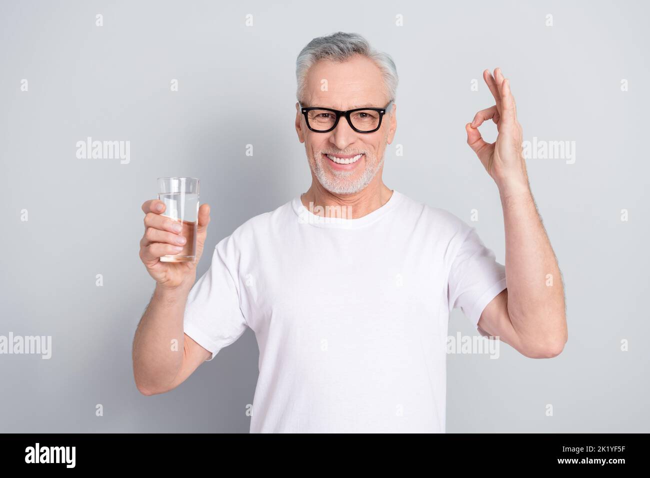 Portrait of cheerful satisfied man hold water glass hand fingers show ...