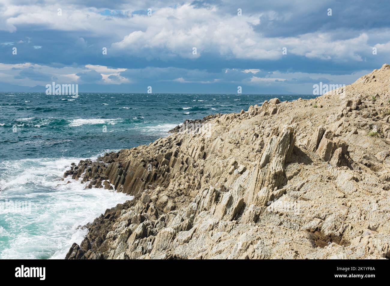 rocky seashore formed by columnar basalt against the backdrop of a sea ...