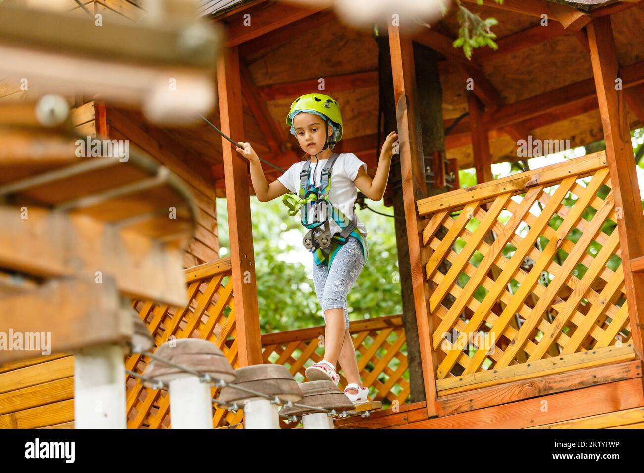 Happy school girl enjoying activity in a climbing adventure park on a ...