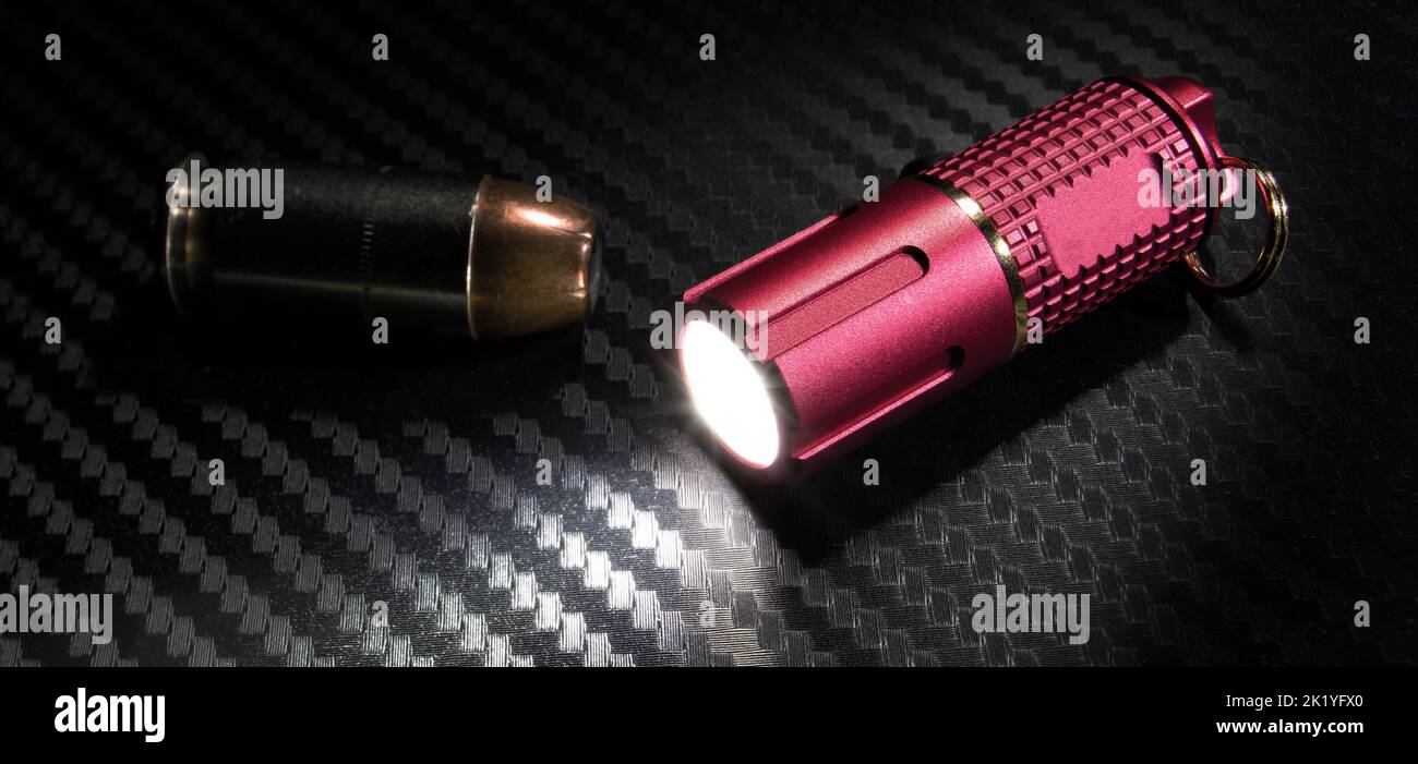 Small pink flashlight that is on next to a semi-auto pistol cartridge ...