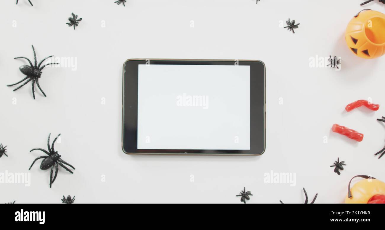 Image of halloween spiders, bats and decorations over tablet on white ...