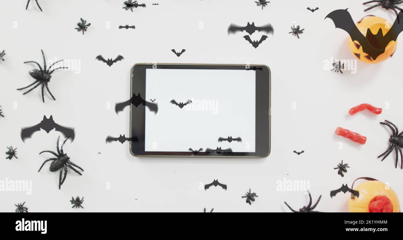 Image of halloween spiders, bats and decorations over tablet on white ...