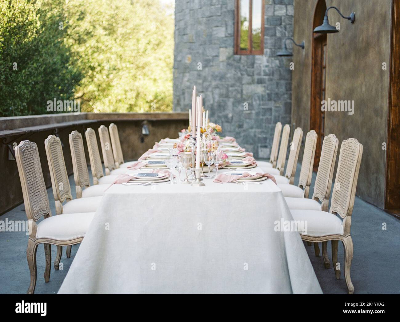 A luxury wedding reception table with white cloth cover with trees in ...
