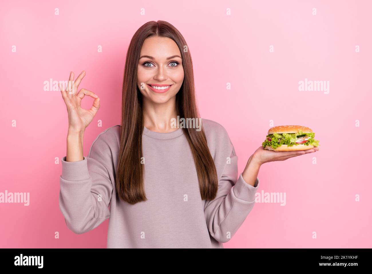 Photo of cheerful lady hand hold burger fingers show okey symbol ...