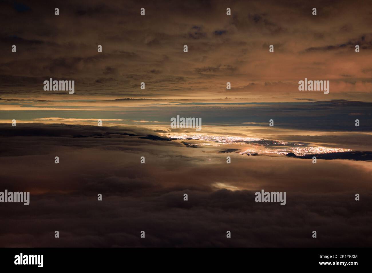 High elevation view of layers of clouds over lights from distant city ...