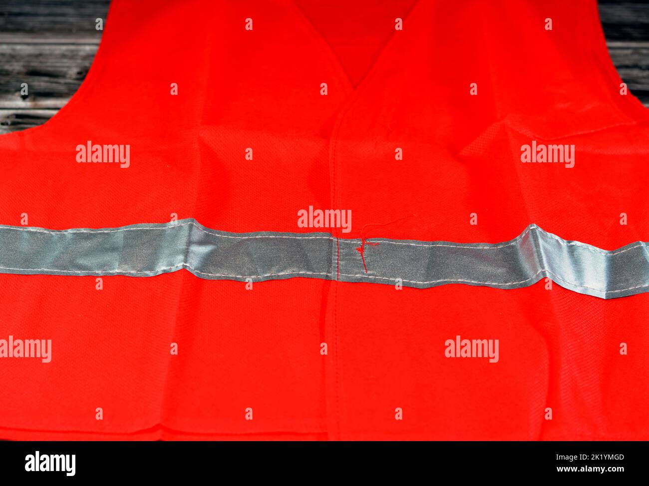 Red reflective safety vest with reflective stripes isolated on wooden ...