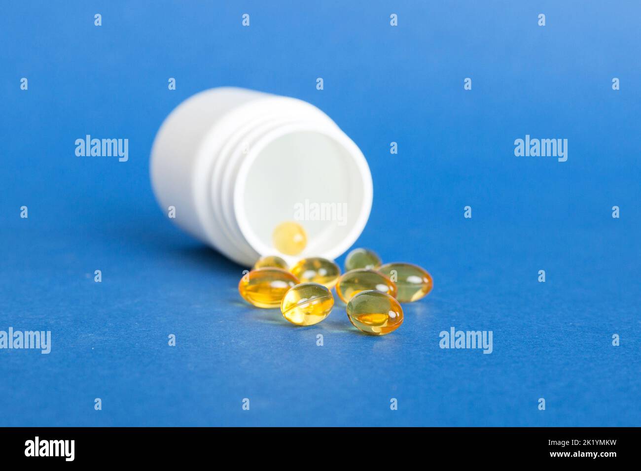 Soft gels pills with Omega-3 oil spilling out of pill bottle close-up ...