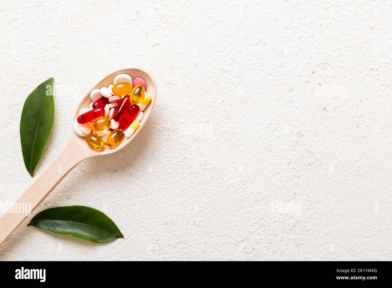 Vitamin capsules in a spoon on a colored background. Pills served as a ...