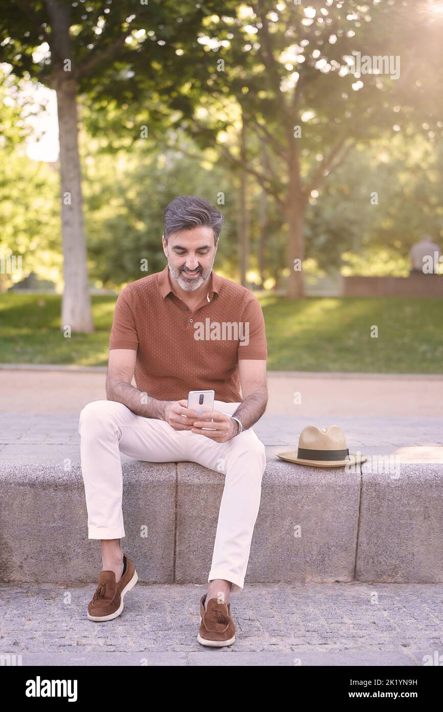 Man relaxing while using a mobile phone outdoors in a park. Technology ...
