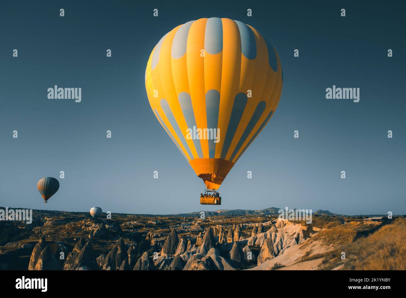 Yellow bright hot air balloon with tourists rise up for sunrise ...