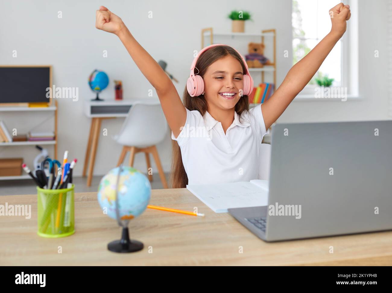 Girl happily and victoriously raises her hands after completing school ...