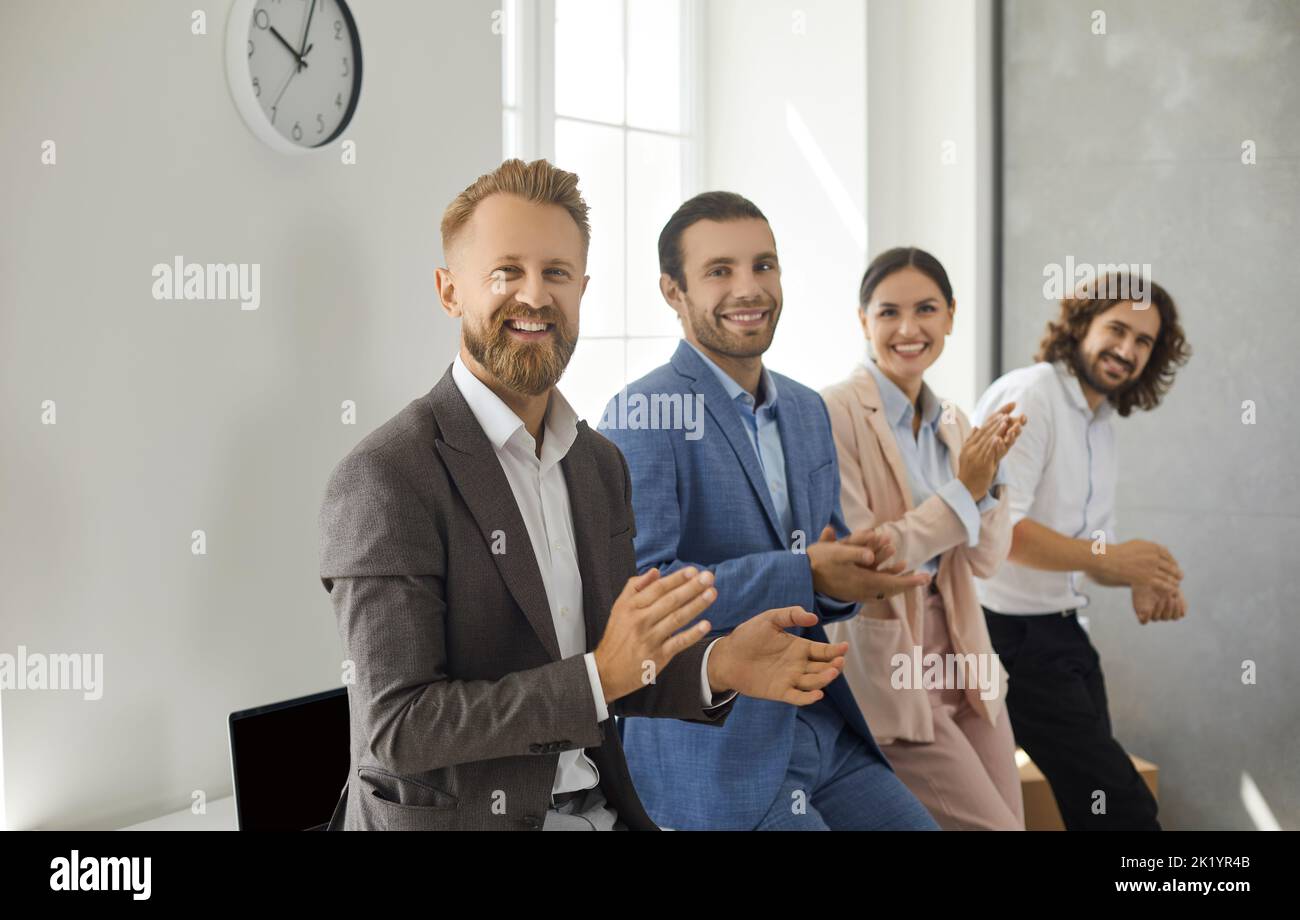 Team of happy business people standing in office, smiling and clapping ...