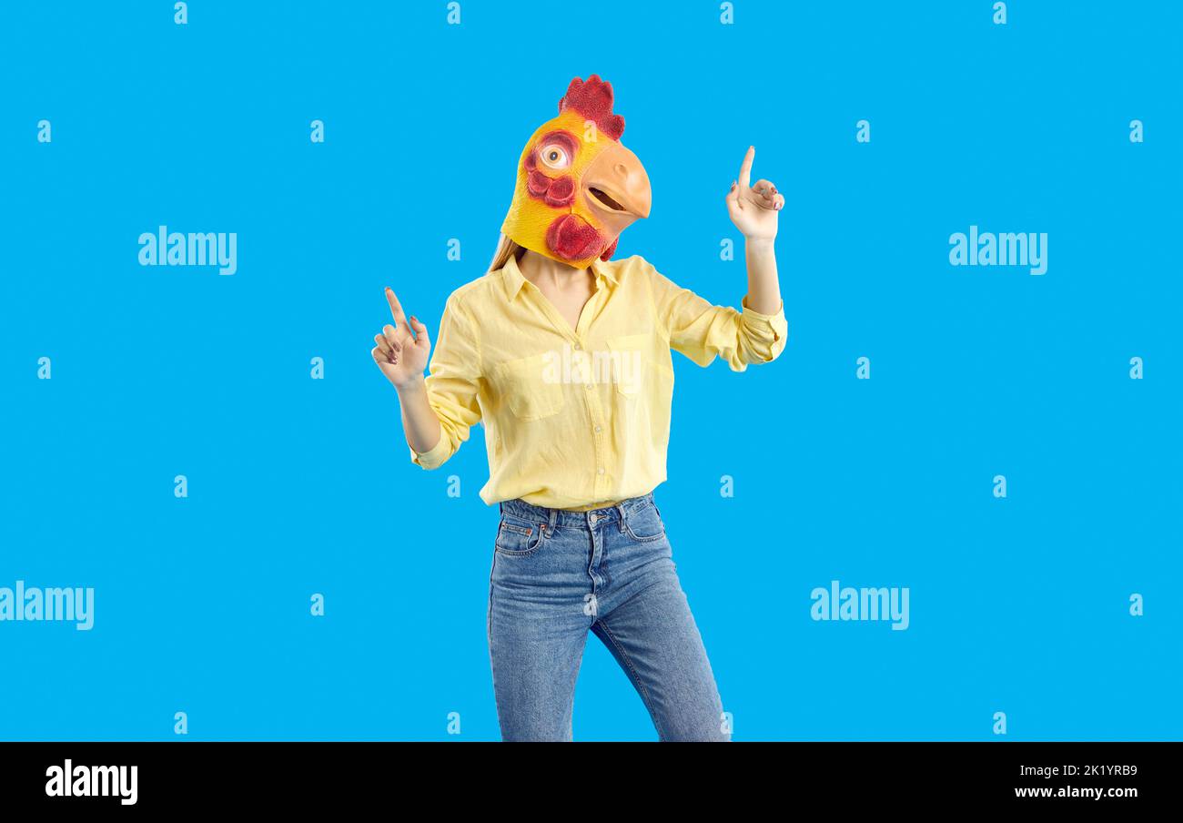 Young girl wearing funny yellow chicken mask dancing isolated on blue ...