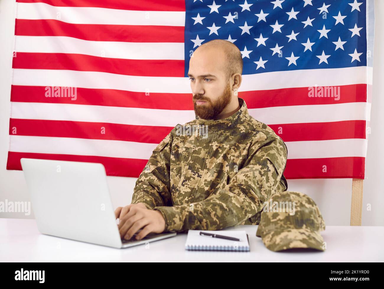 American soldier working on laptop while sitting at office desk with ...