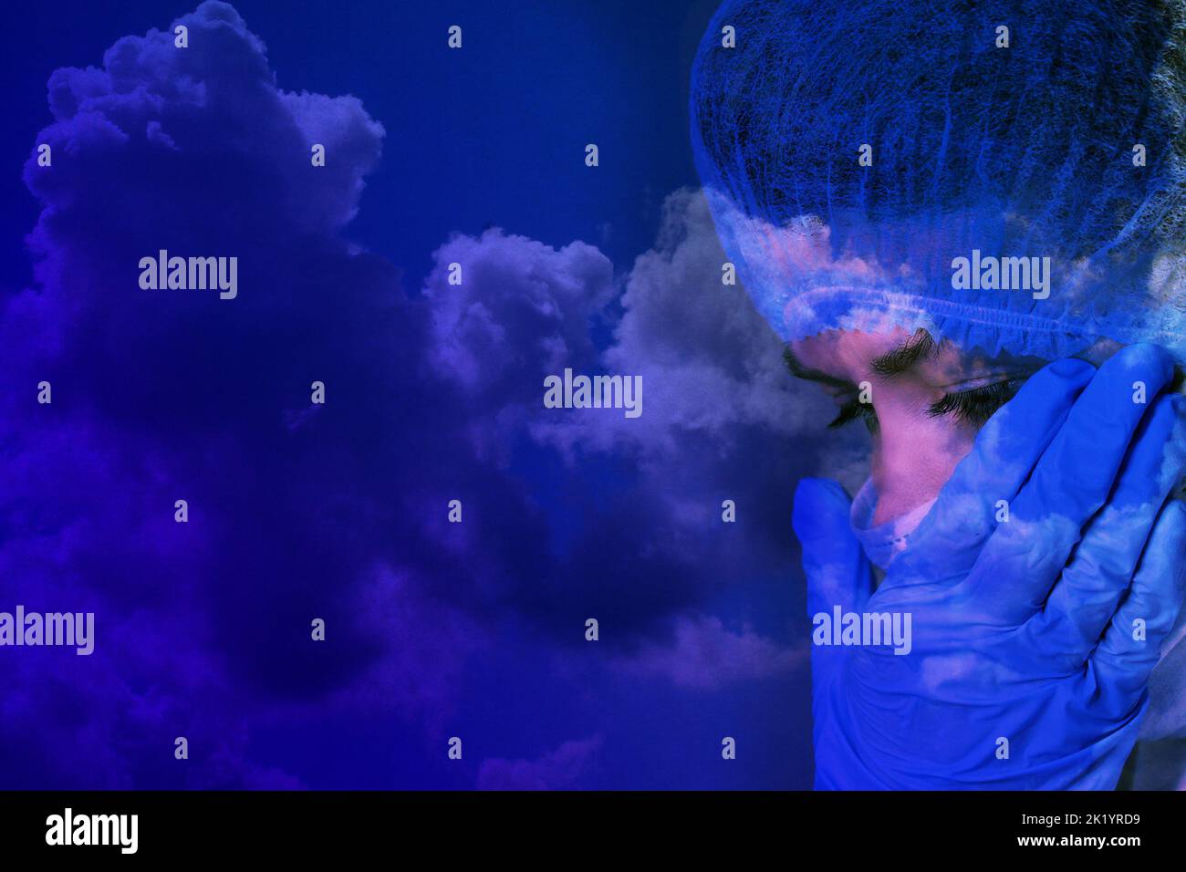 A woman doctor in a medical mask and gloves is crying against the ...