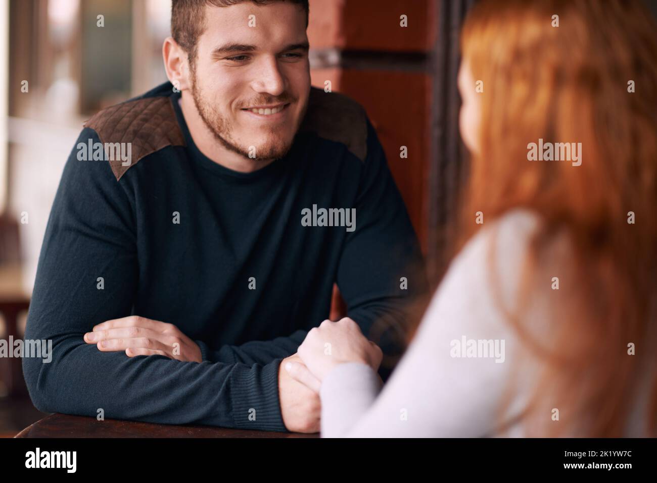 Hes totally smitten. a young affectionate couple holding hands while on ...