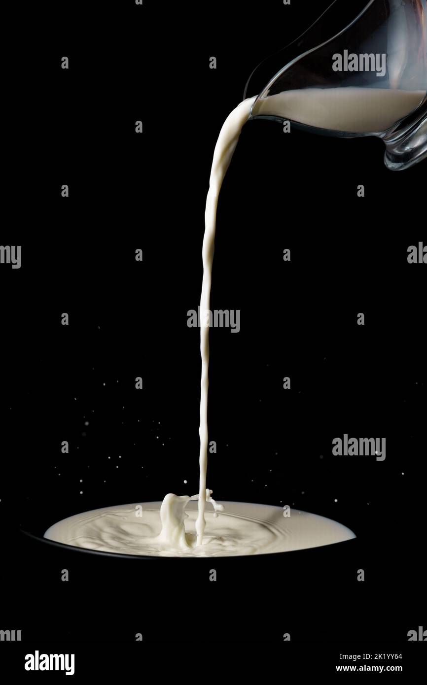 pitcher pouring milk into a splash plate effect Stock Photo - Alamy