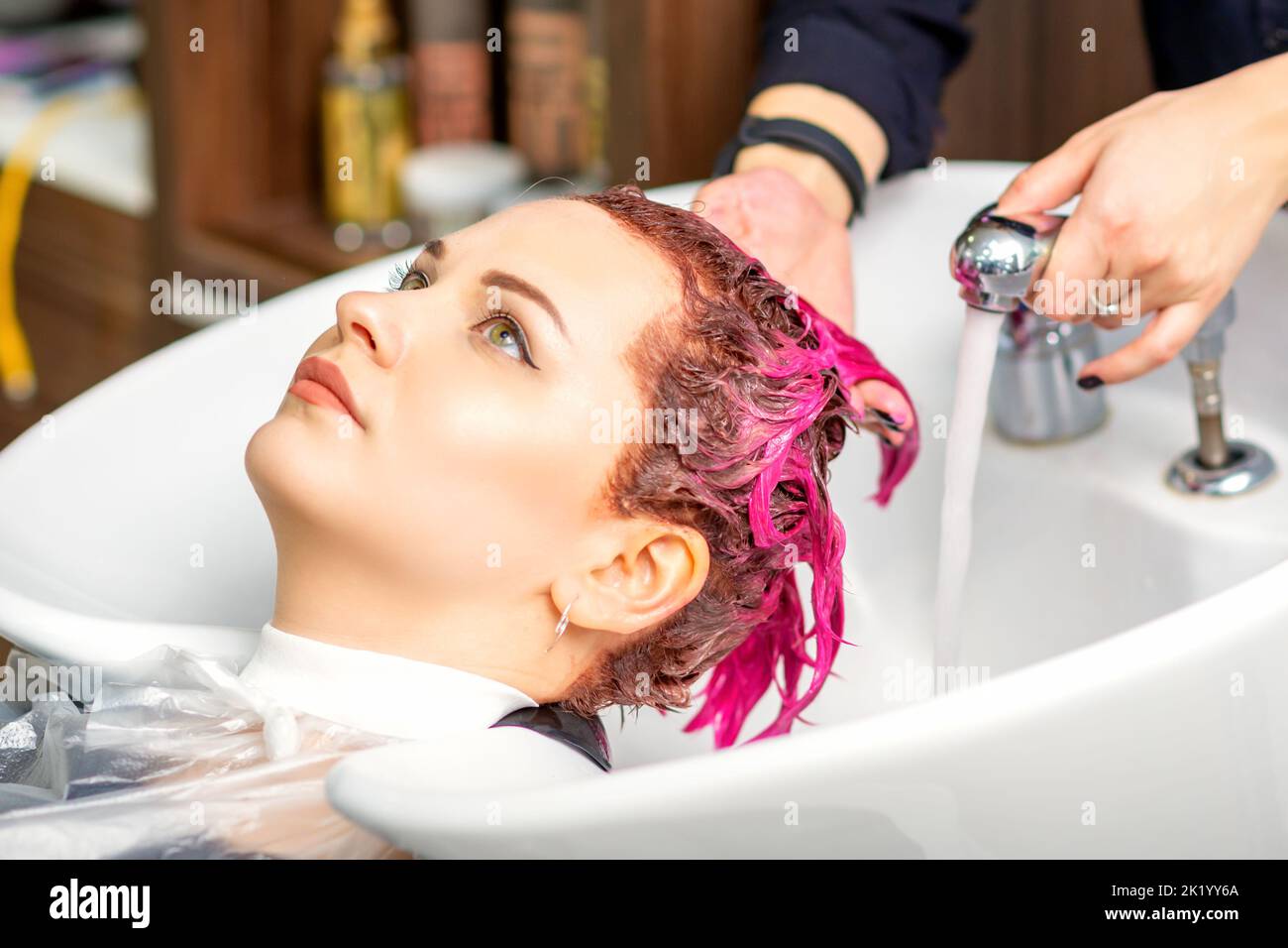 Washing dyed female hair. A young caucasian woman having her hair ...
