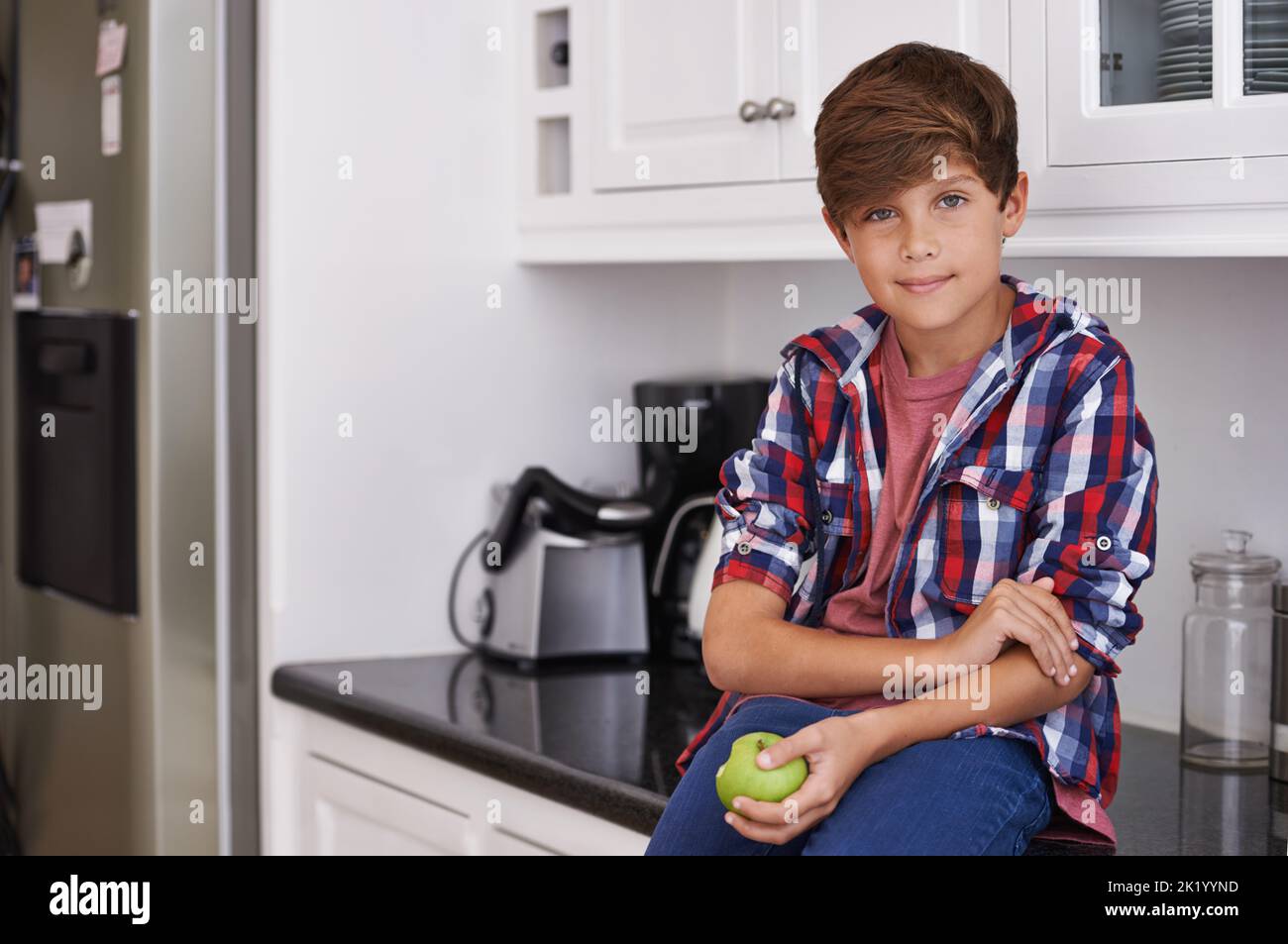 Apples are yum. a young boy sitting on the kitchen counter with an ...