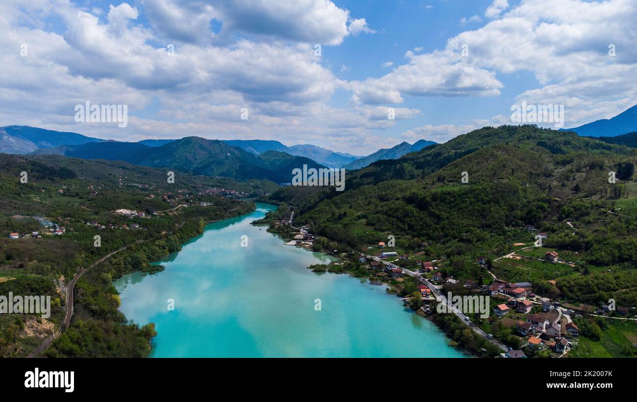 A bird's eye view of an azure river between villages on mountains in ...