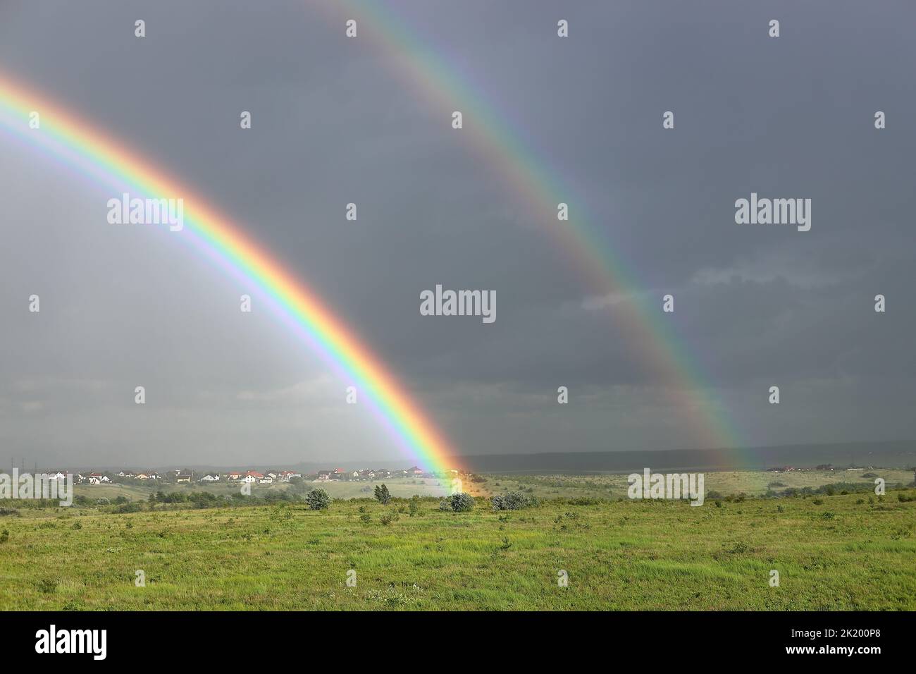 Bright double rainbow with dark rain clouds in the background Stock ... Bright double rainbow with dark rain clouds in the background Stock ...
