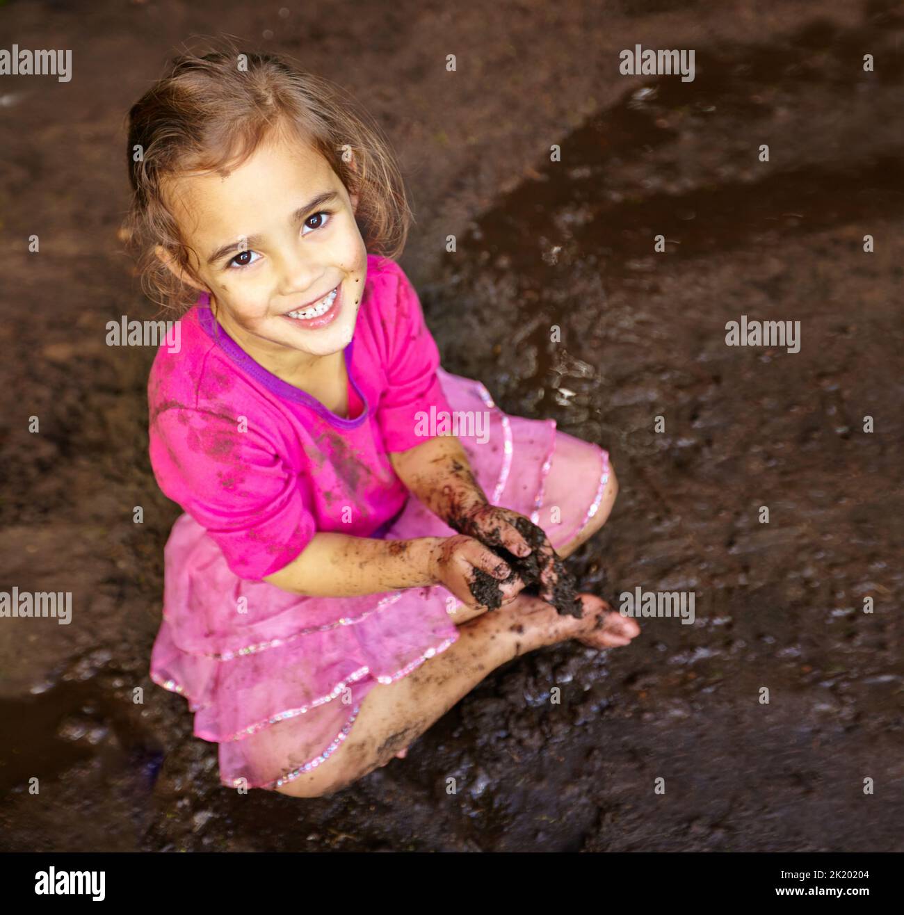 Muddy fun and games. Portrait of a little girl playing outside in the ...