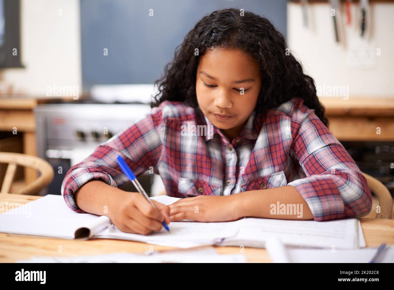 Shes one focused student. a young girl studying at a desk in a ...