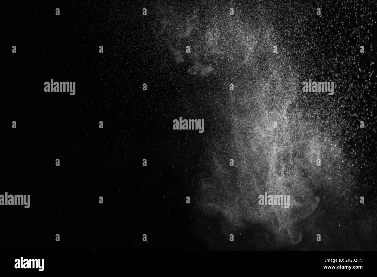 Stream of white curly steam with water drops on a black background ...