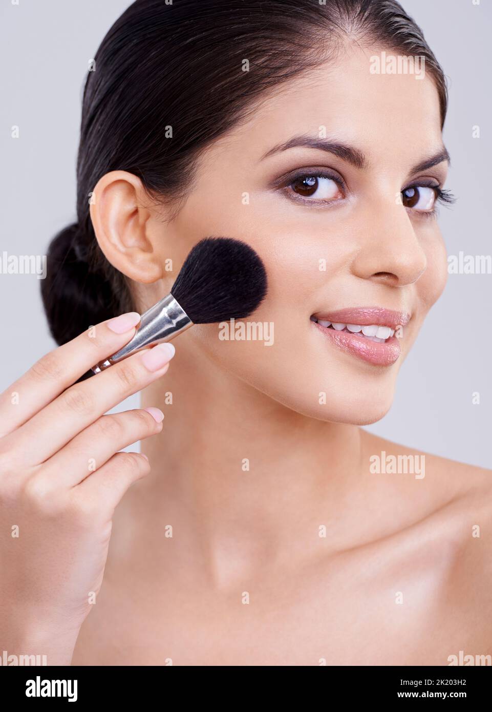 Getting her cheeks nice and rosy. a beautiful young woman applying ...