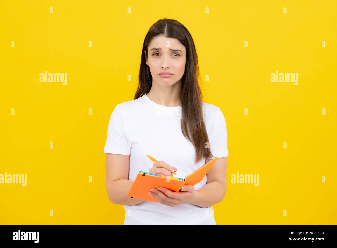Sad tired woman isolated over yellow background writing notes in ...