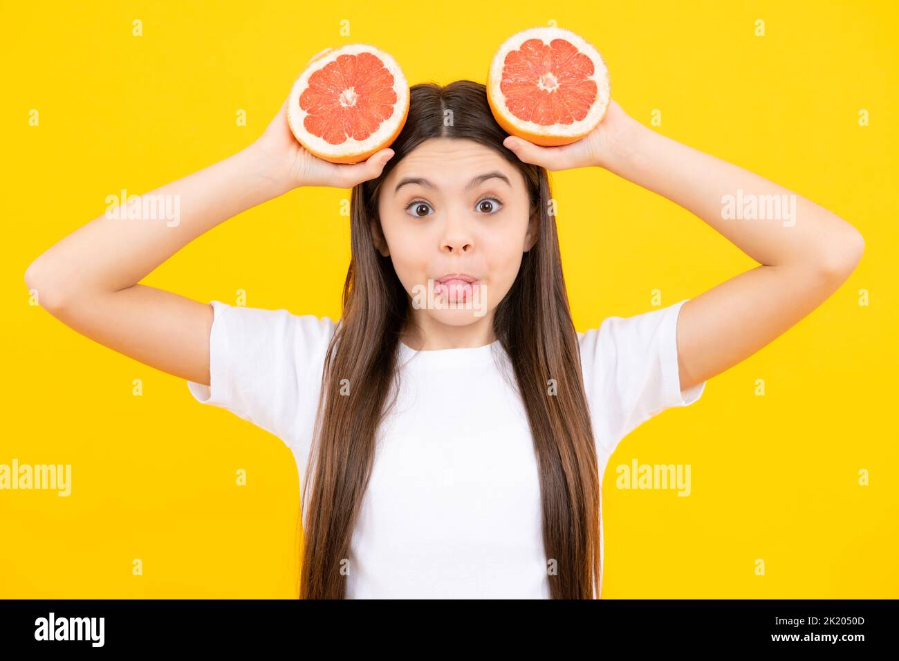 Funny face. Teen girl with grapefruit. Vitamin and fruits. Child eating ...