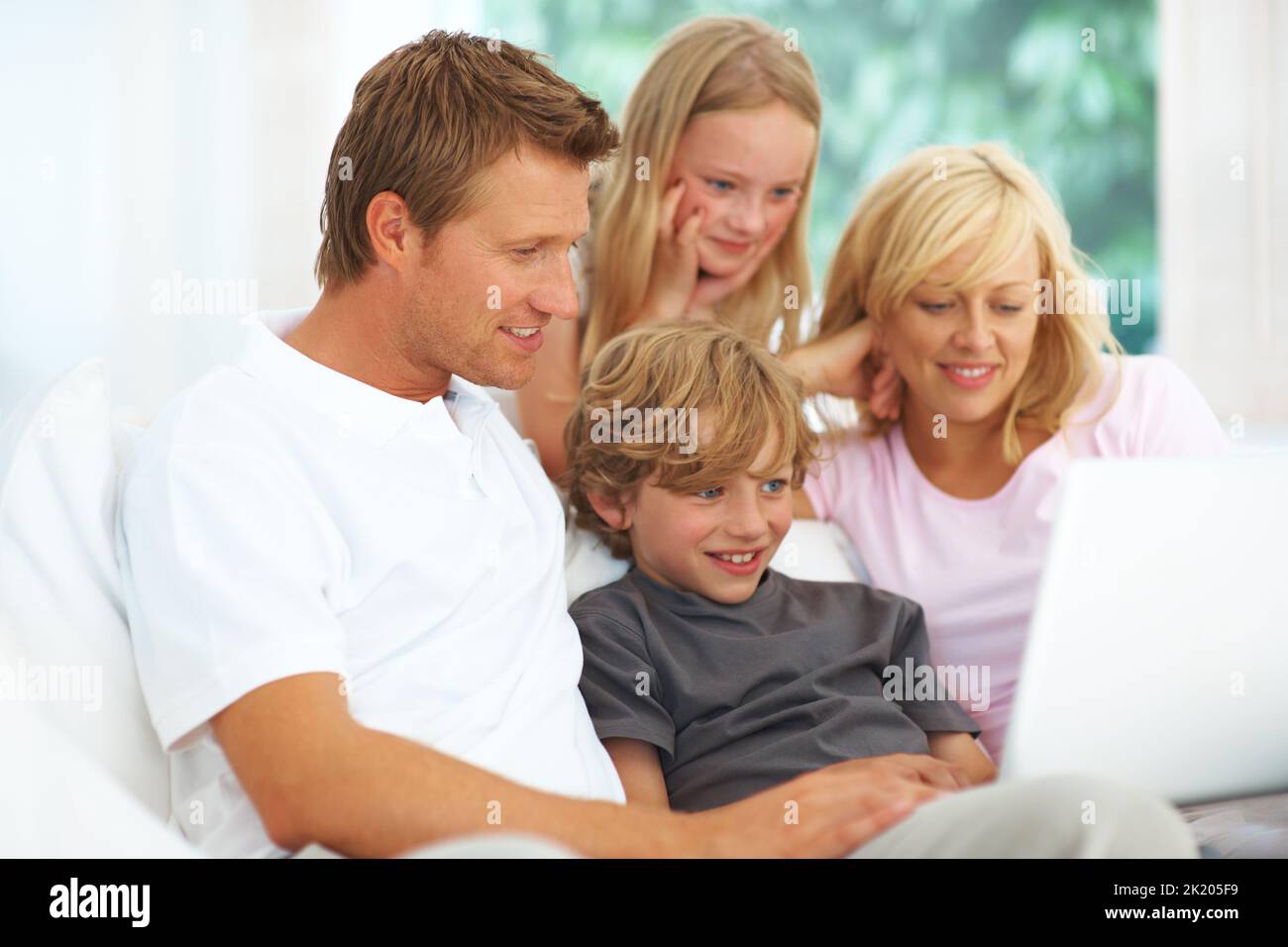 Exploring technology together. Happy young family using a laptop ...