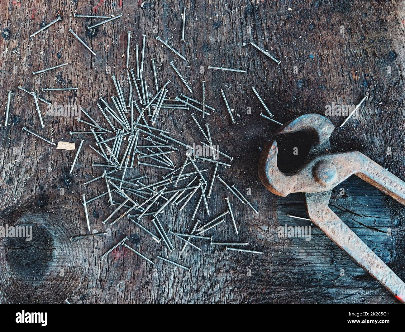 A pile of nails and rusty pliers on a weathered wood background Stock ...