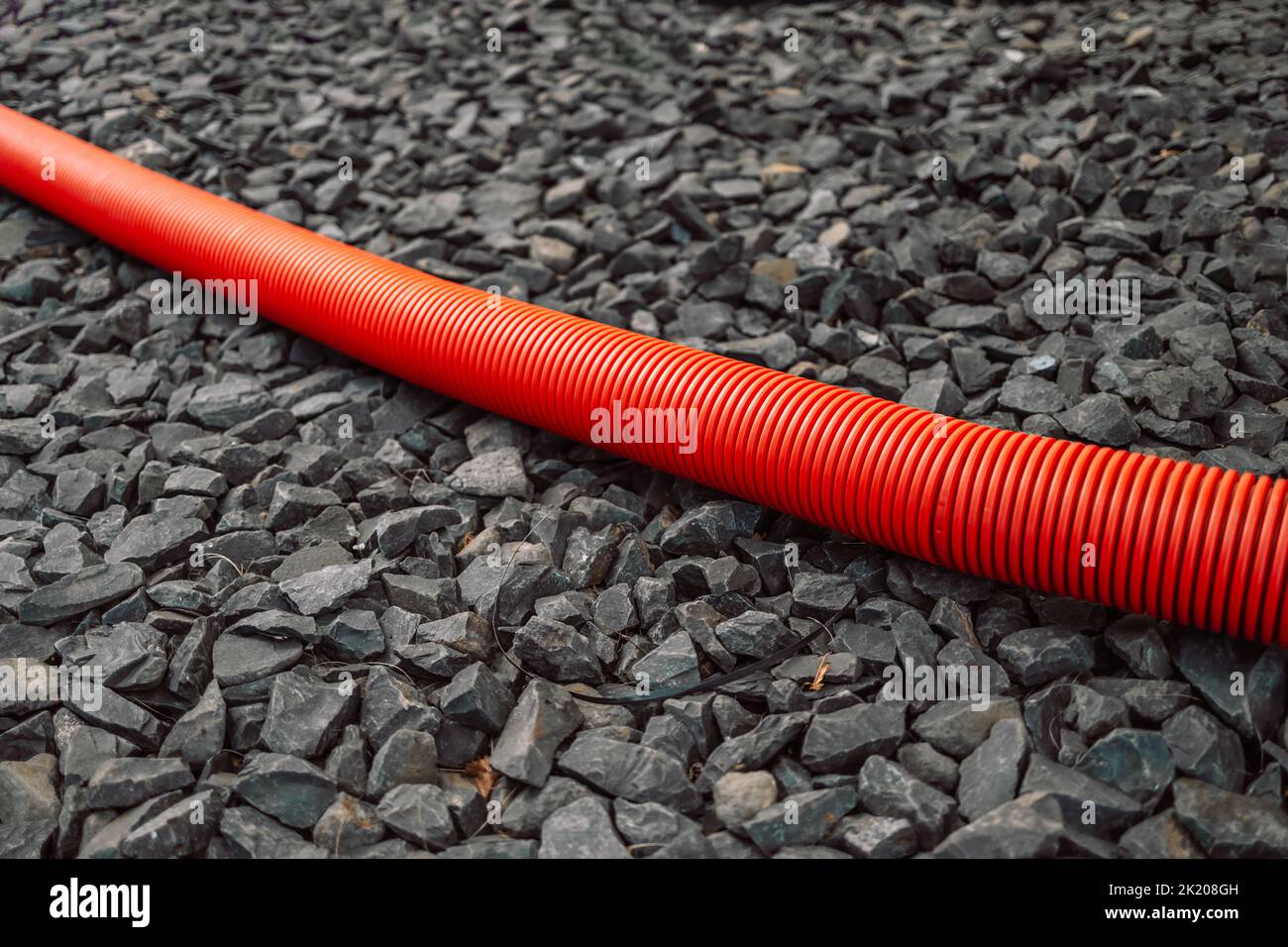 Plastic pipe for underground utilities of red color lie on ground Stock ...