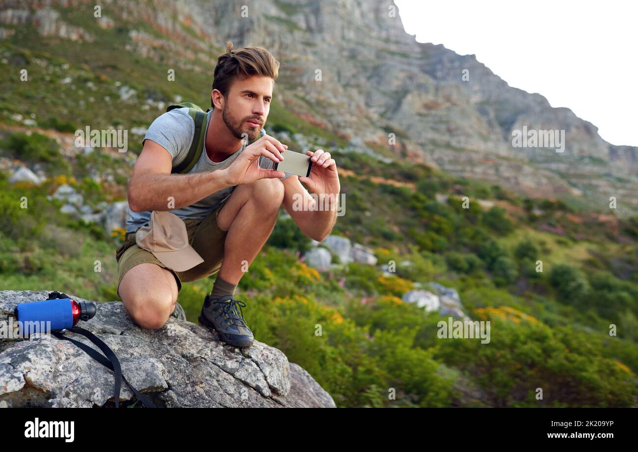 Capturing the moment. a handsome young man snapping pics while hiking ...