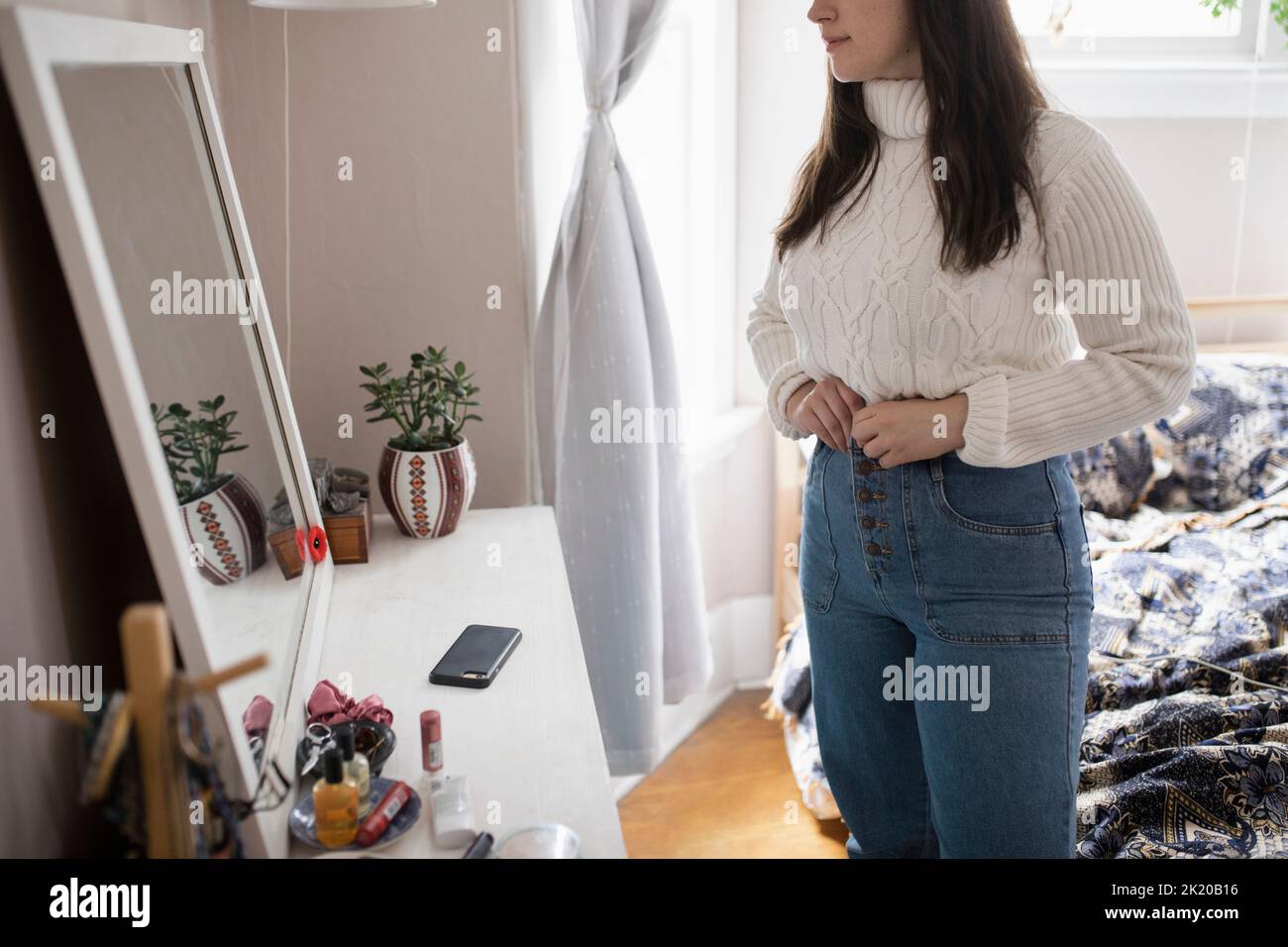 Woman getting dressed in bedroom Stock Photo - Alamy